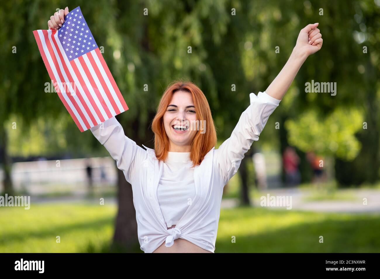 Angry young red haired woman protester posing with USA national flag in ...