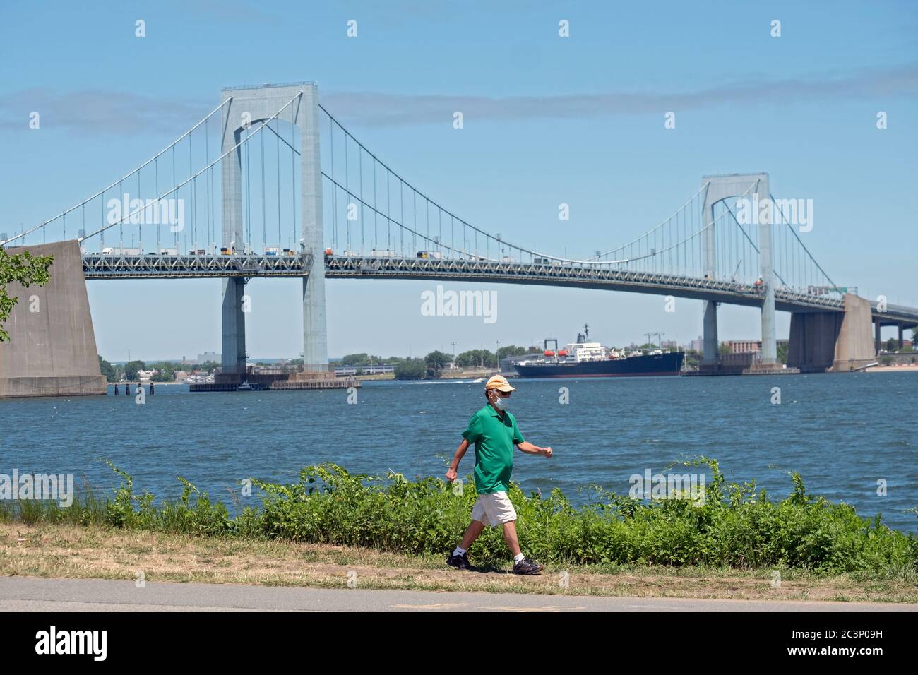 In the shadow of the Throgs Neck Bridge, a man wearing a surgical mask ...