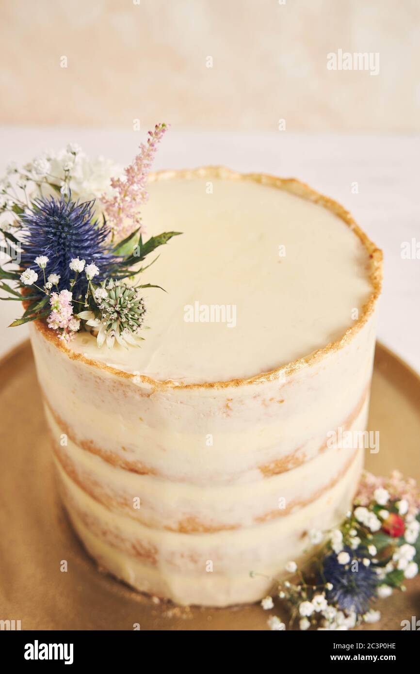 Vertical shot of a beautiful and delicious cake with flower and golden ...