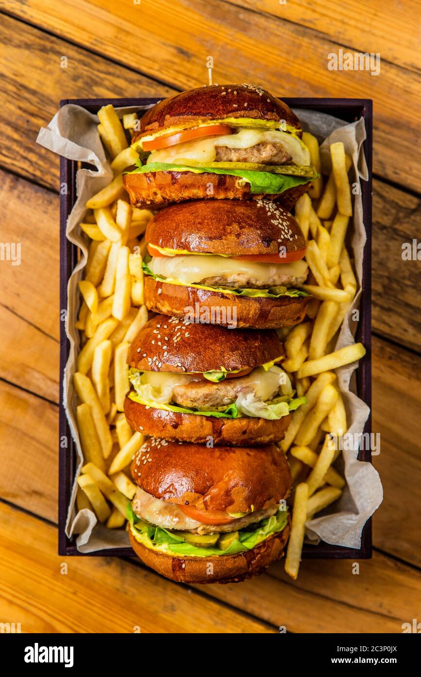 A stack of burgers and french fries in a box on a wooden table, top ...