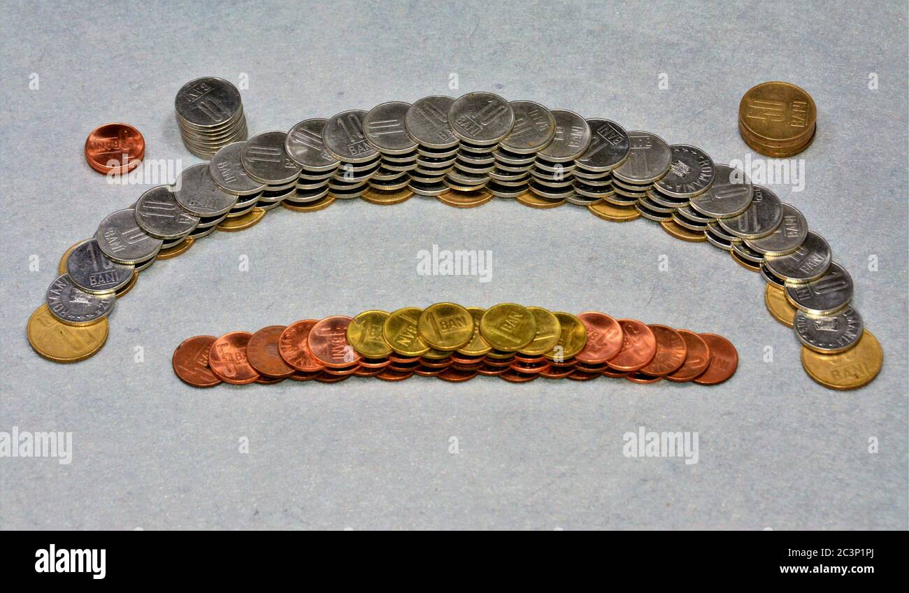 High angle closeup shot of different coins in the shape of a sad face ...