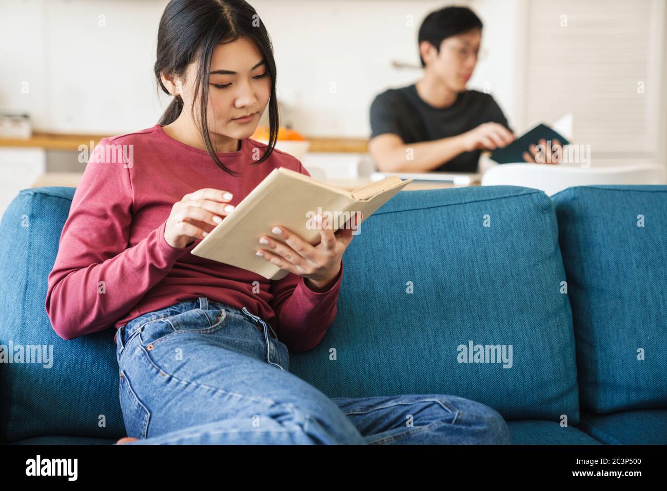 Photo of young concentrated asian couple reading books while sitting at ...