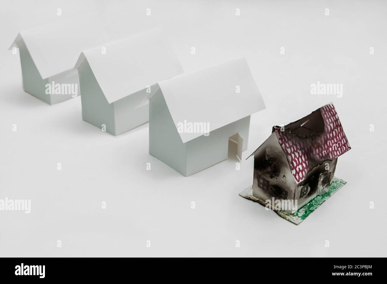 Cardboard tiny houses, one burned. Copy-space, isolated Stock Photo - Alamy