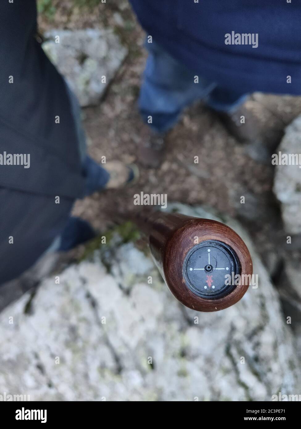 Vertical overhead shot of a compass stick in the stones with two people ...