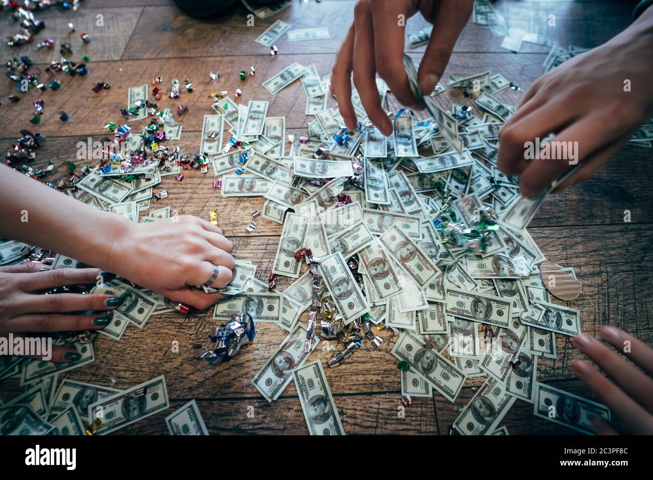 Several pairs of hands pick up dollar bills from the floor Stock Photo ...