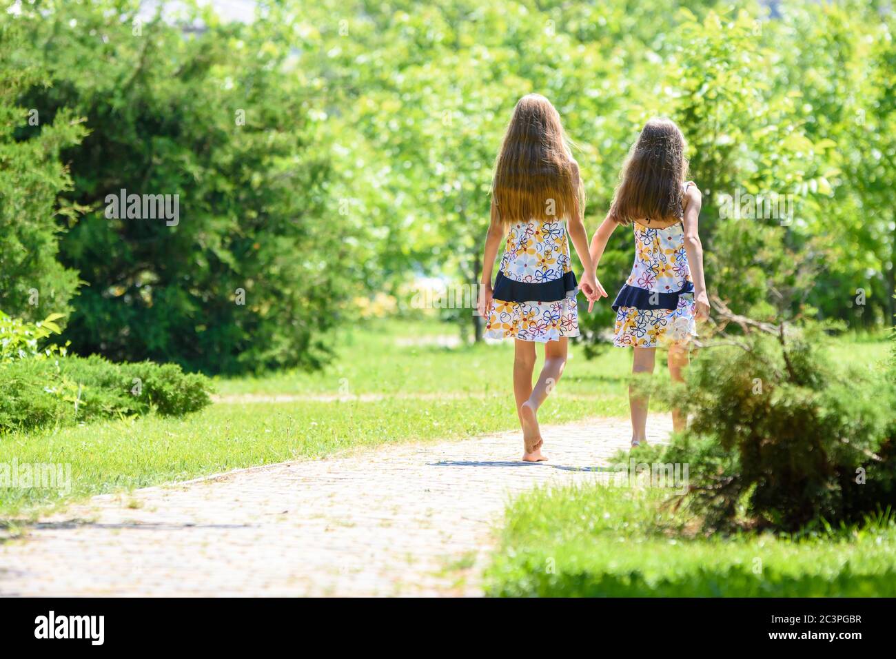Two girls walk along a path in a beautiful city park Stock Photo - Alamy