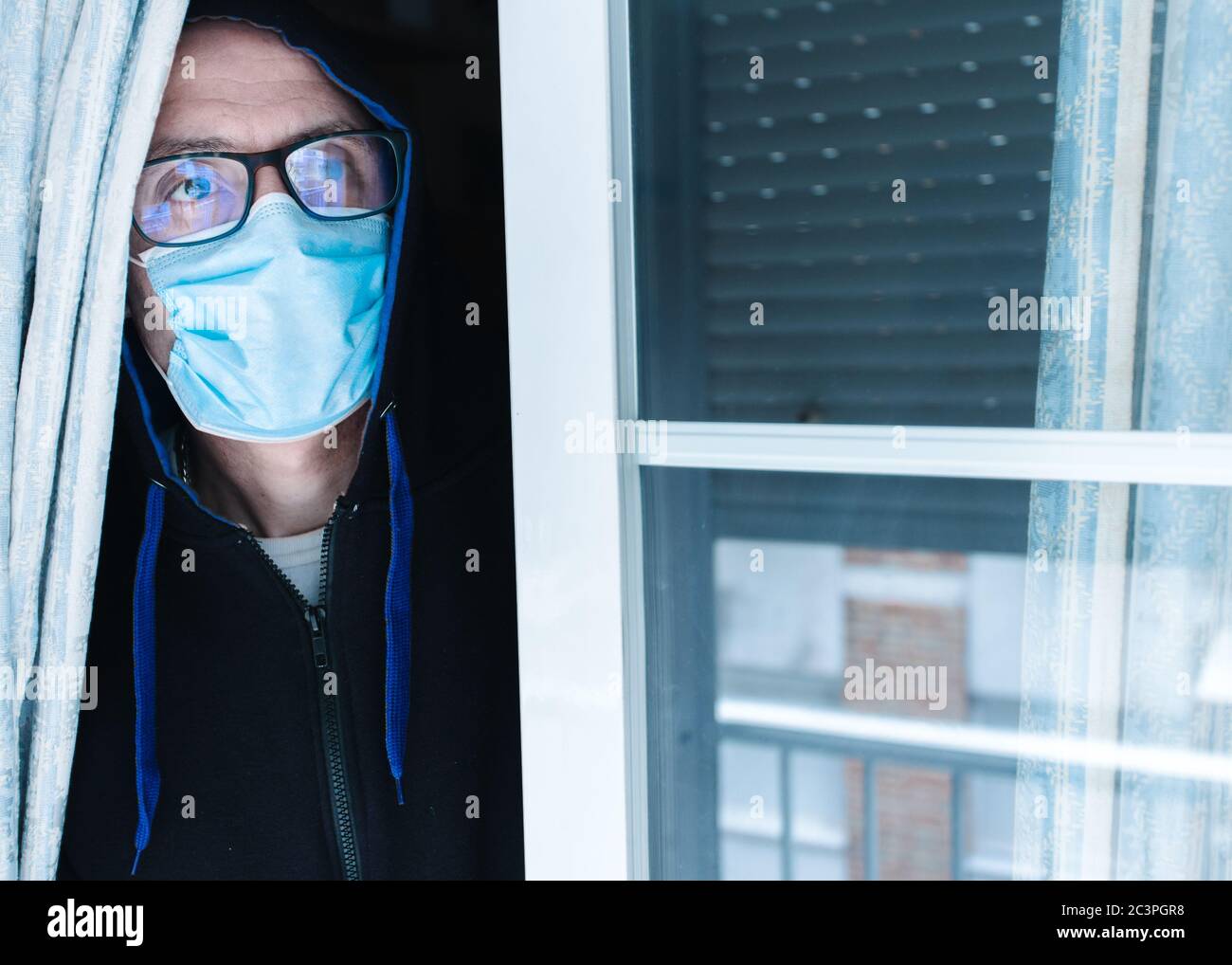 Male wearing glasses and a sanitary face mask while standing behind a ...
