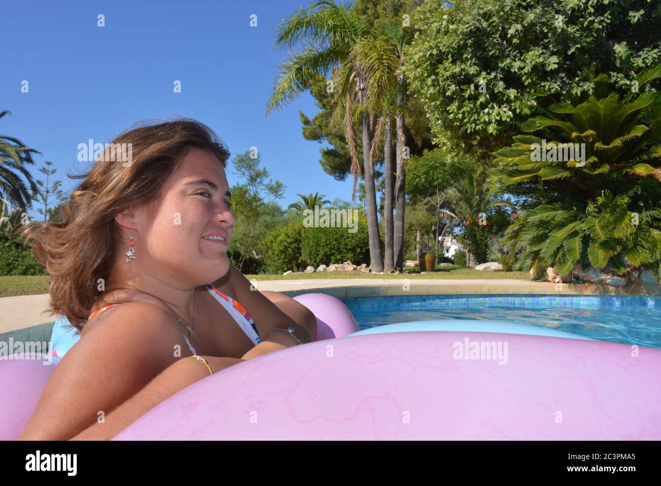 Beautiful Young Woman Floating On A Lilo In A Swimming Pool On A Bright And Sunny Summer Day