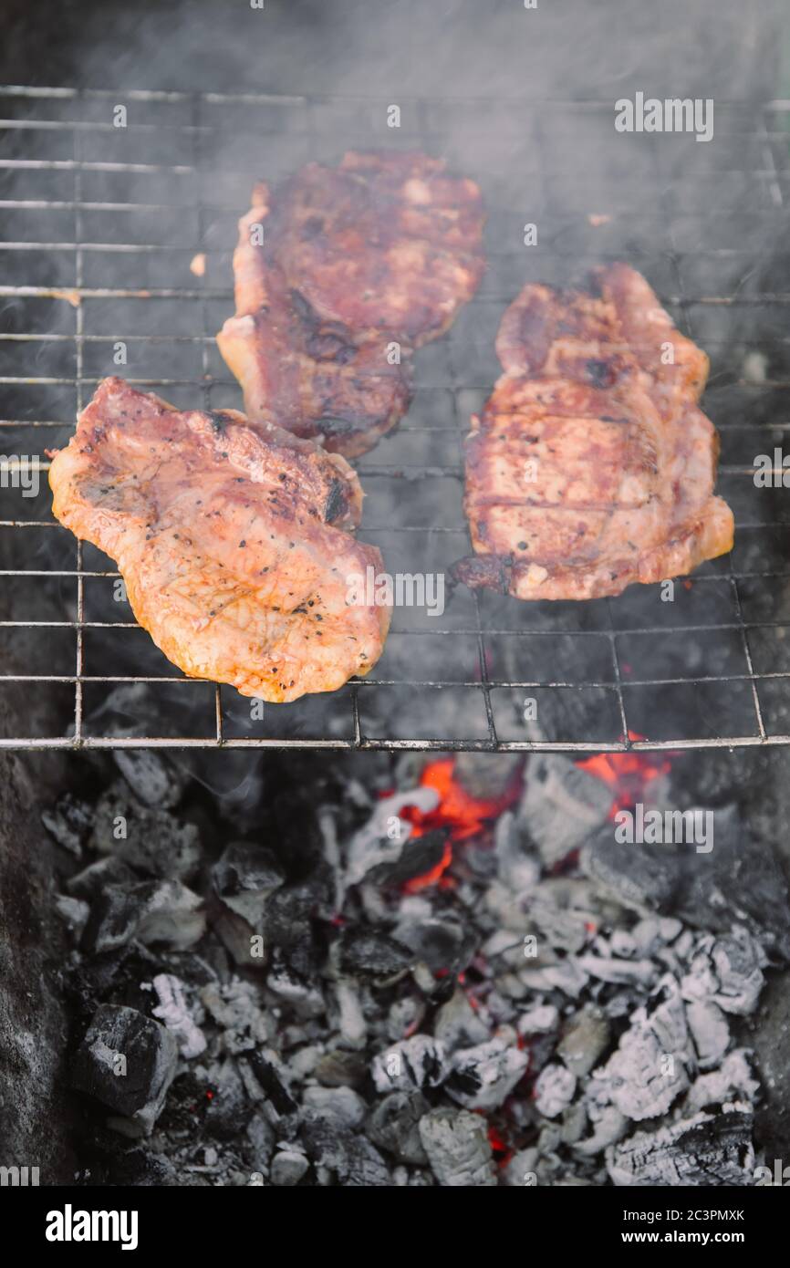 cooking meat over hot coals on a wire rack with a shallow depth of ...