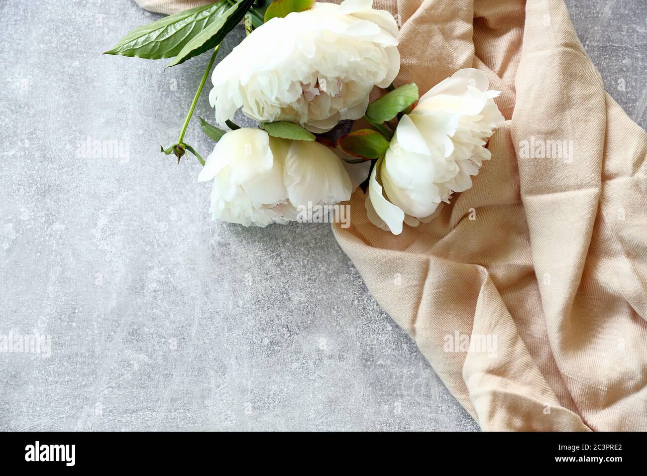 Beige cloth and peony flowers on stone background. Flat lay, top view ...