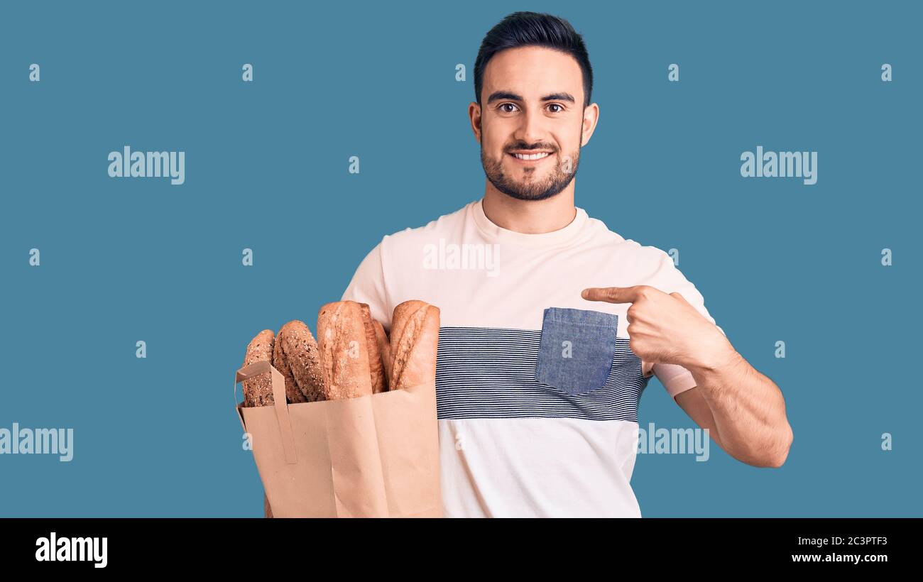 Young handsome man holding bread bag pointing finger to one self ...
