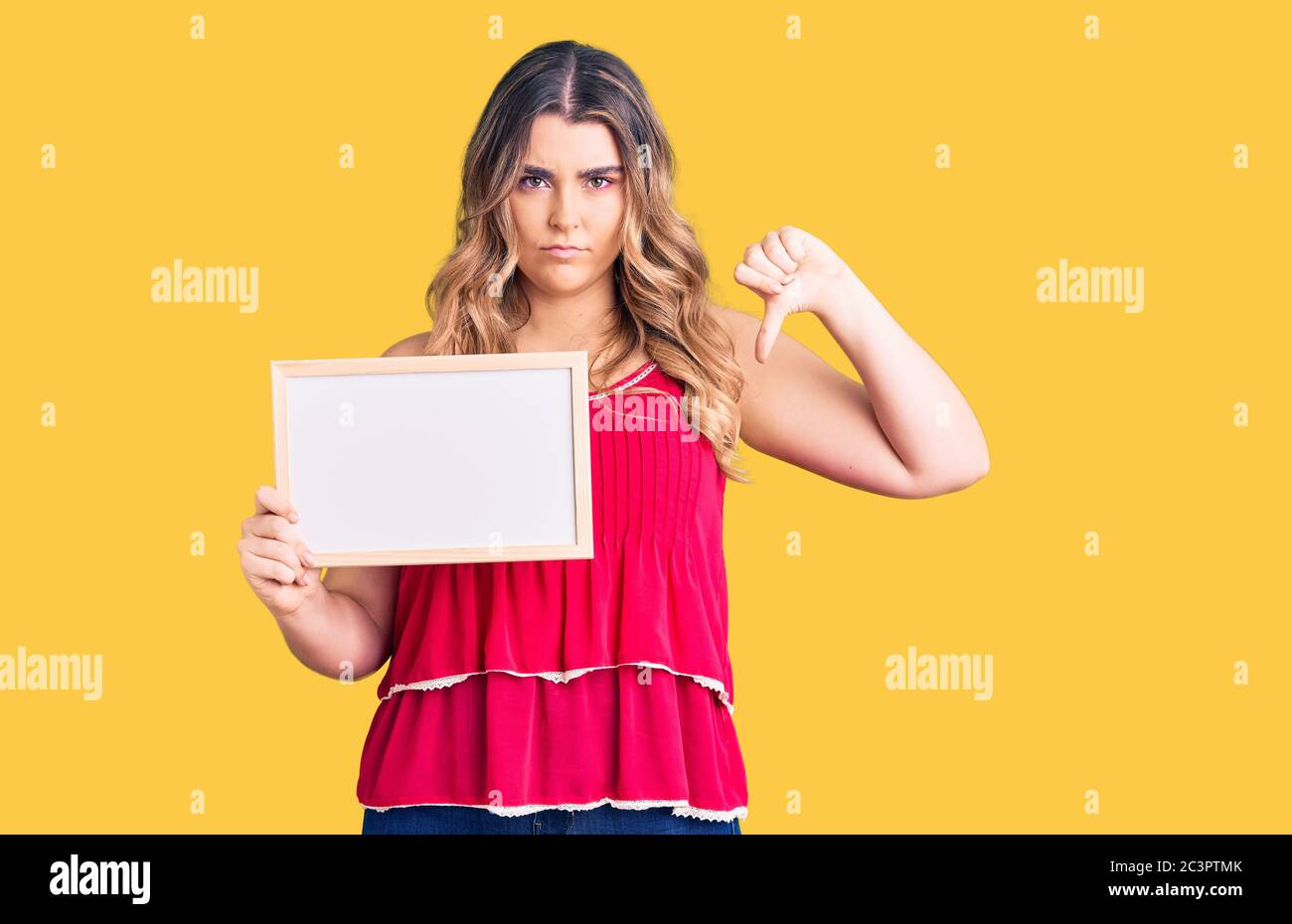 Young caucasian woman holding empty white chalkboard with angry face ...