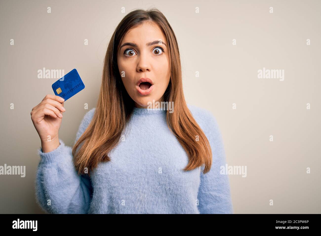 Young blonde woman holding credit card as payment over isolated ...