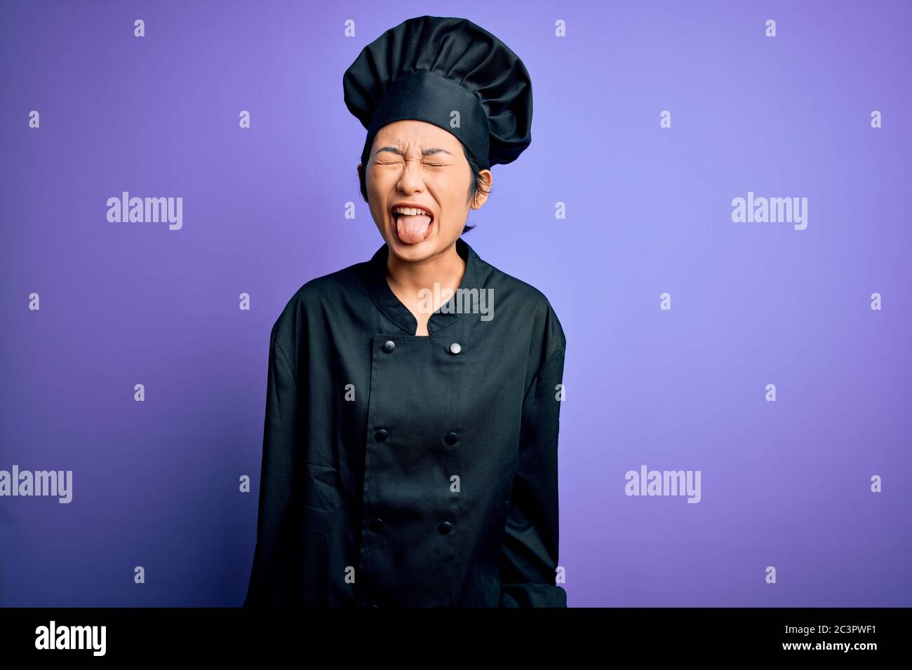 Young beautiful chinese chef woman wearing cooker uniform and hat over ...