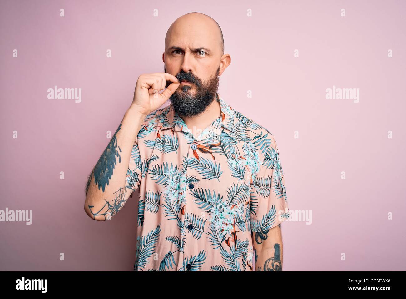 Handsome bald man with beard and tattoo wearing casual floral shirt ...