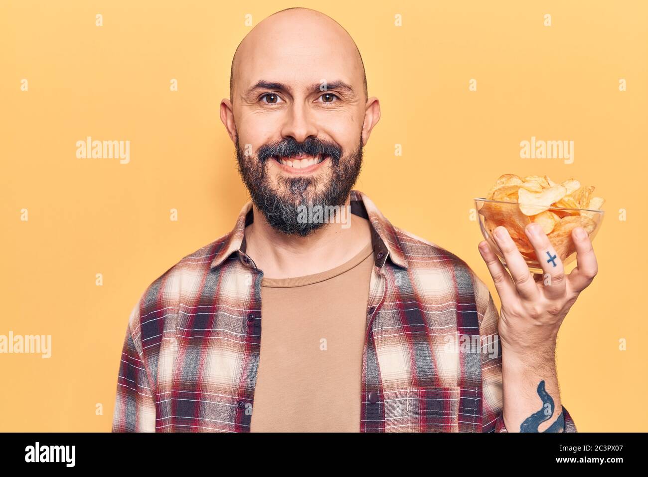 Young handsome man holding potato chip looking positive and happy ...