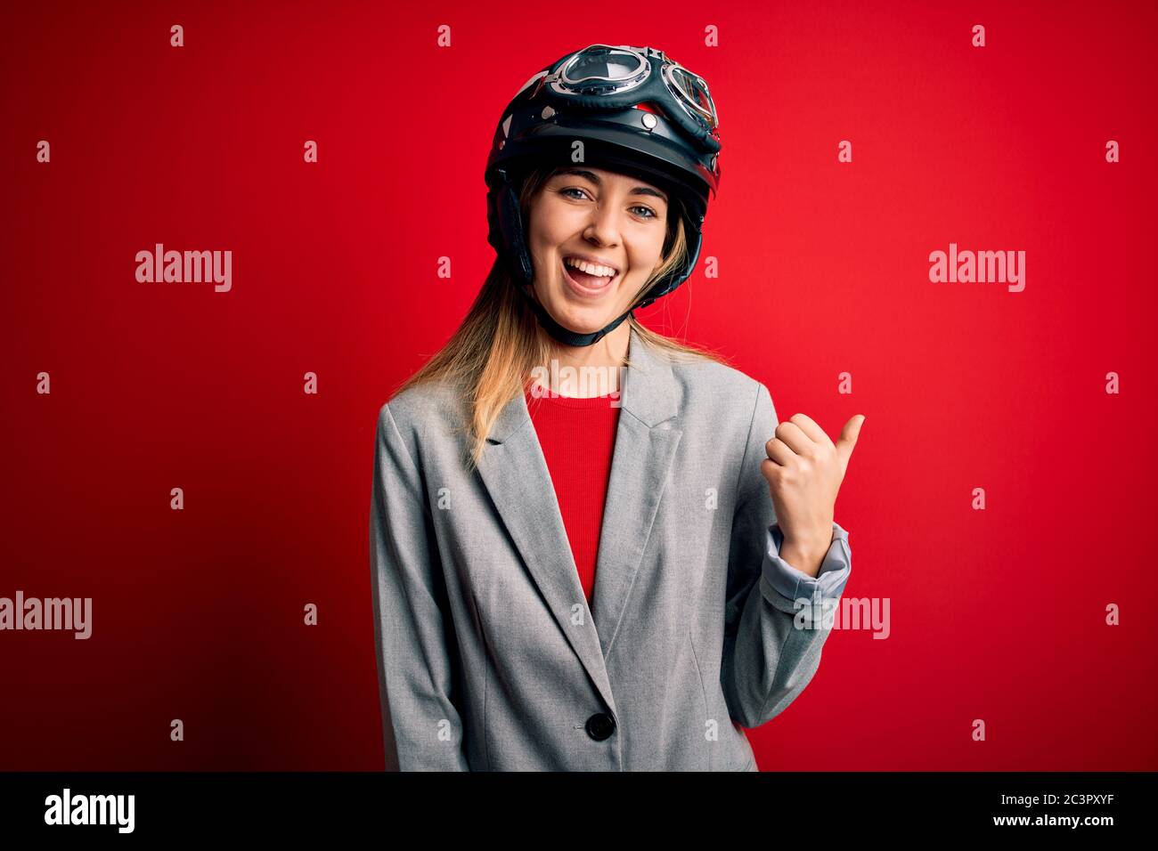 Young beautiful blonde motorcyclist woman wearing motorcycle helmet ...
