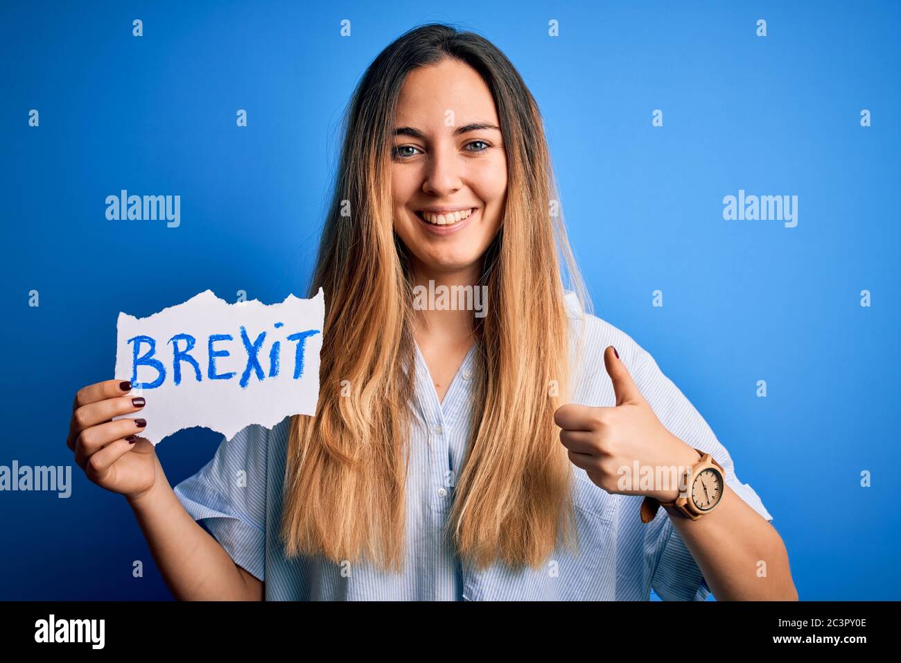Young beautiful blonde woman with blue eyes holding banner with brexit ...