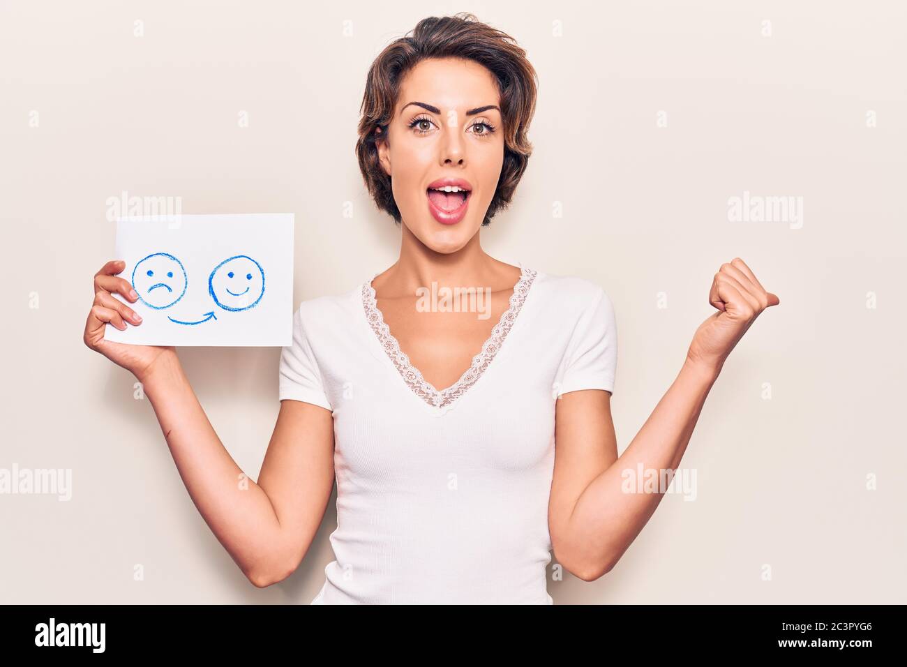 Young beautiful woman holding sad to happy emotion paper pointing thumb ...