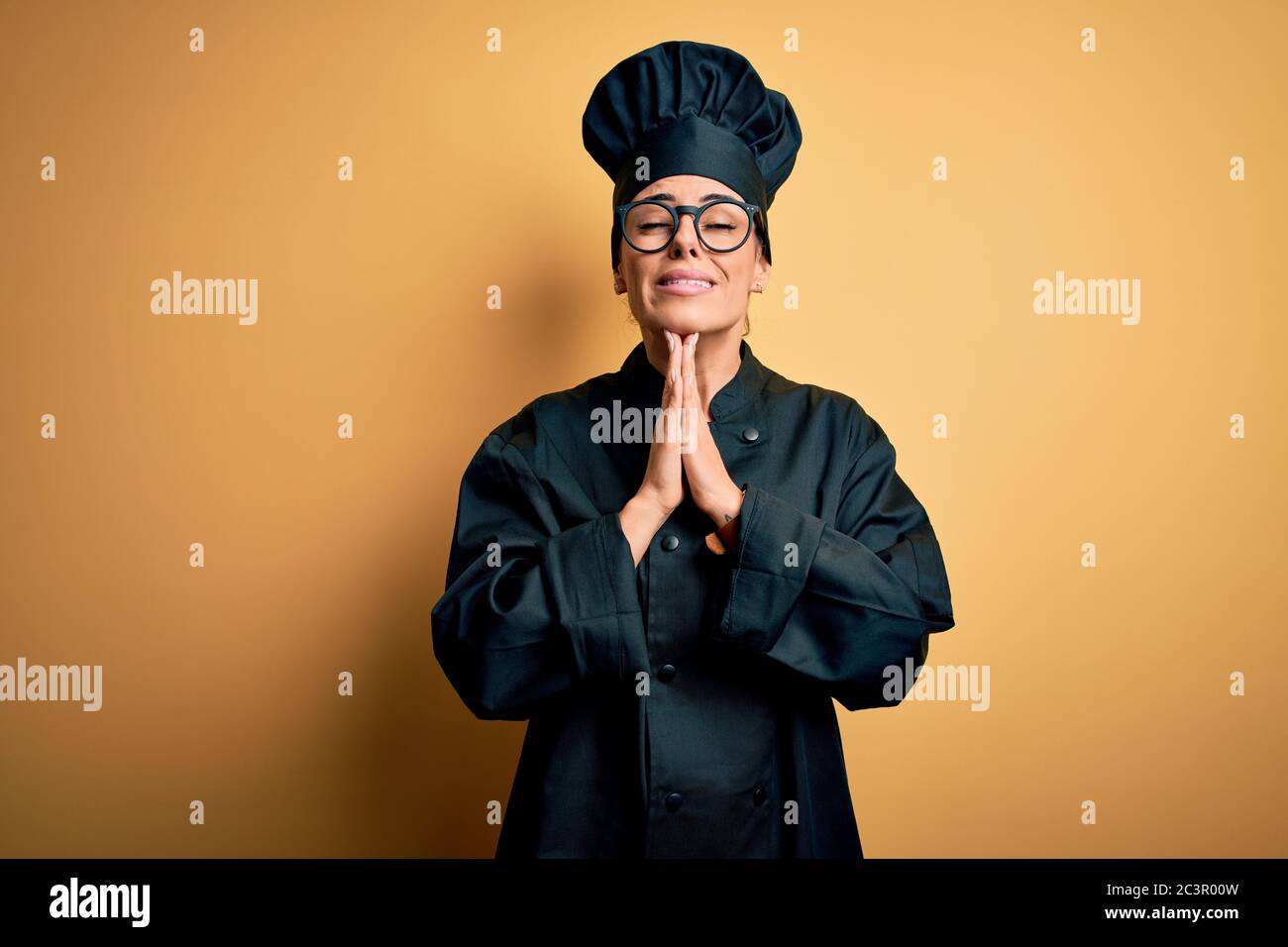 Young beautiful brunette chef woman wearing cooker uniform and hat over ...