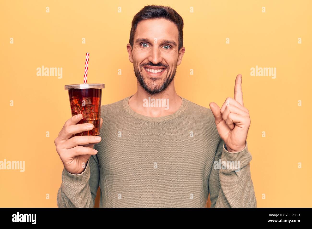 Young handsome man drinking cola refreshment beverage over isolated ...