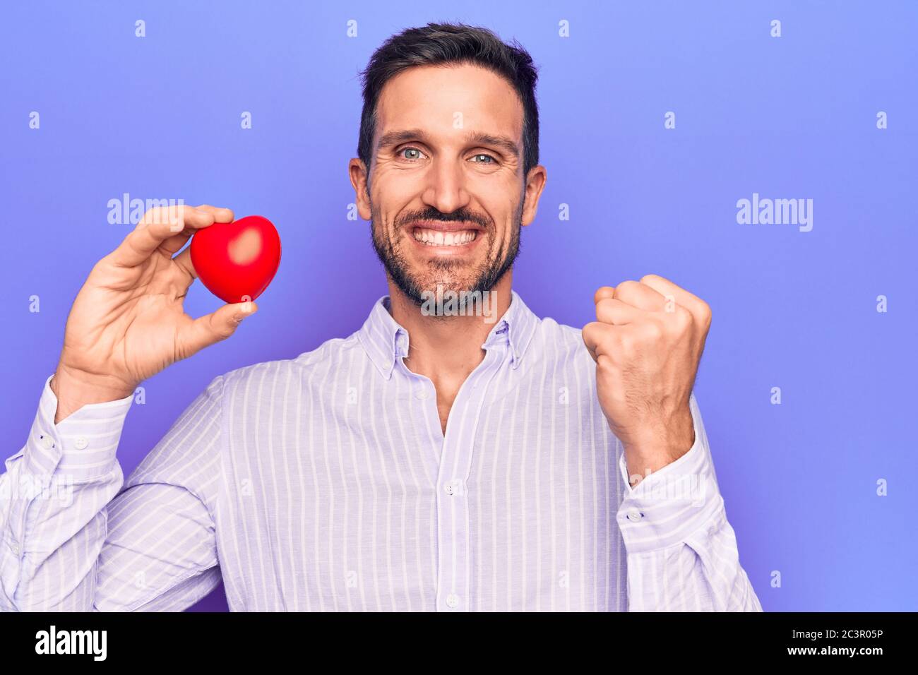 Young handsome man asking for health care holding red heart over ...