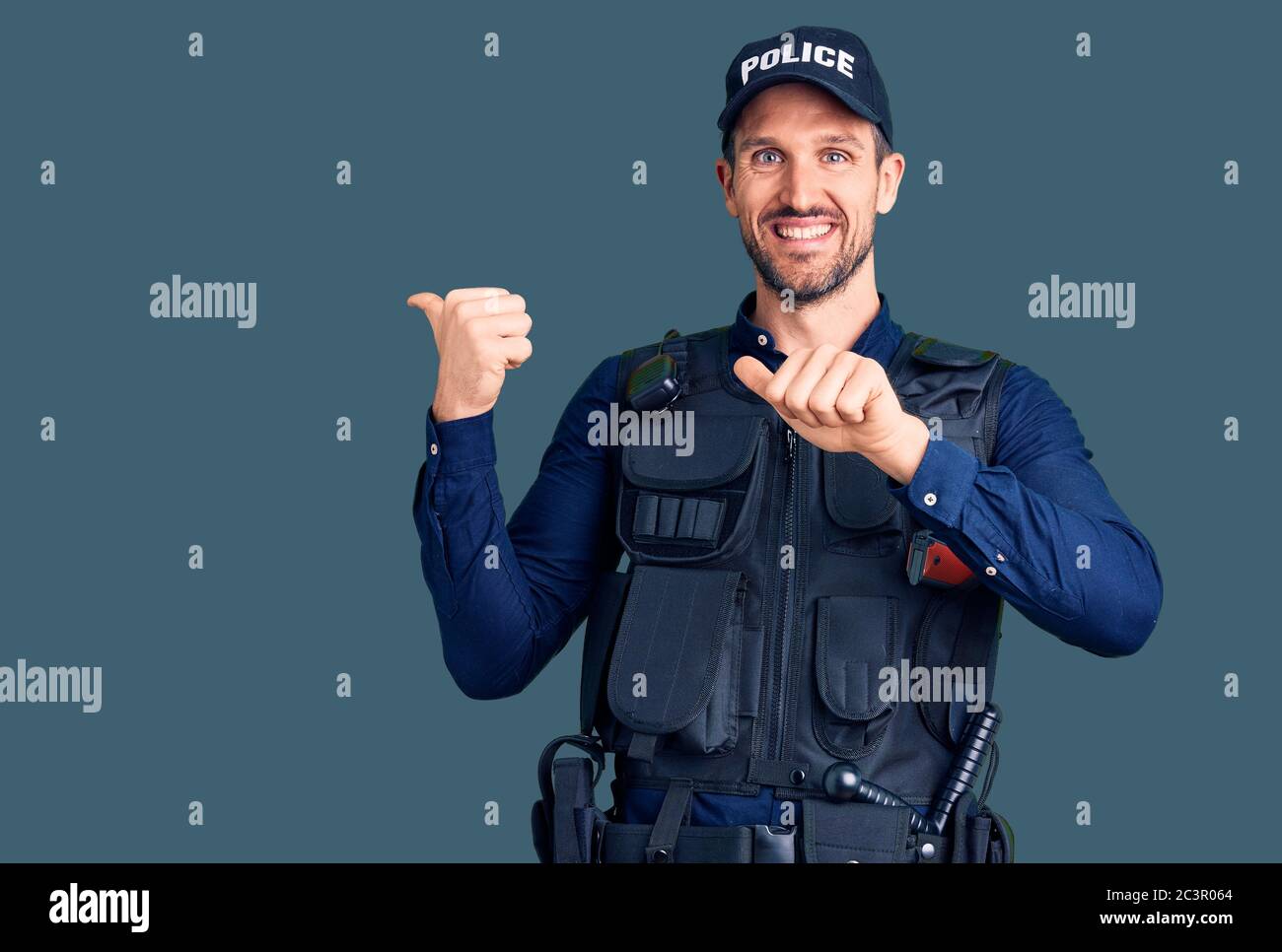 Young handsome man wearing police uniform pointing to the back behind ...