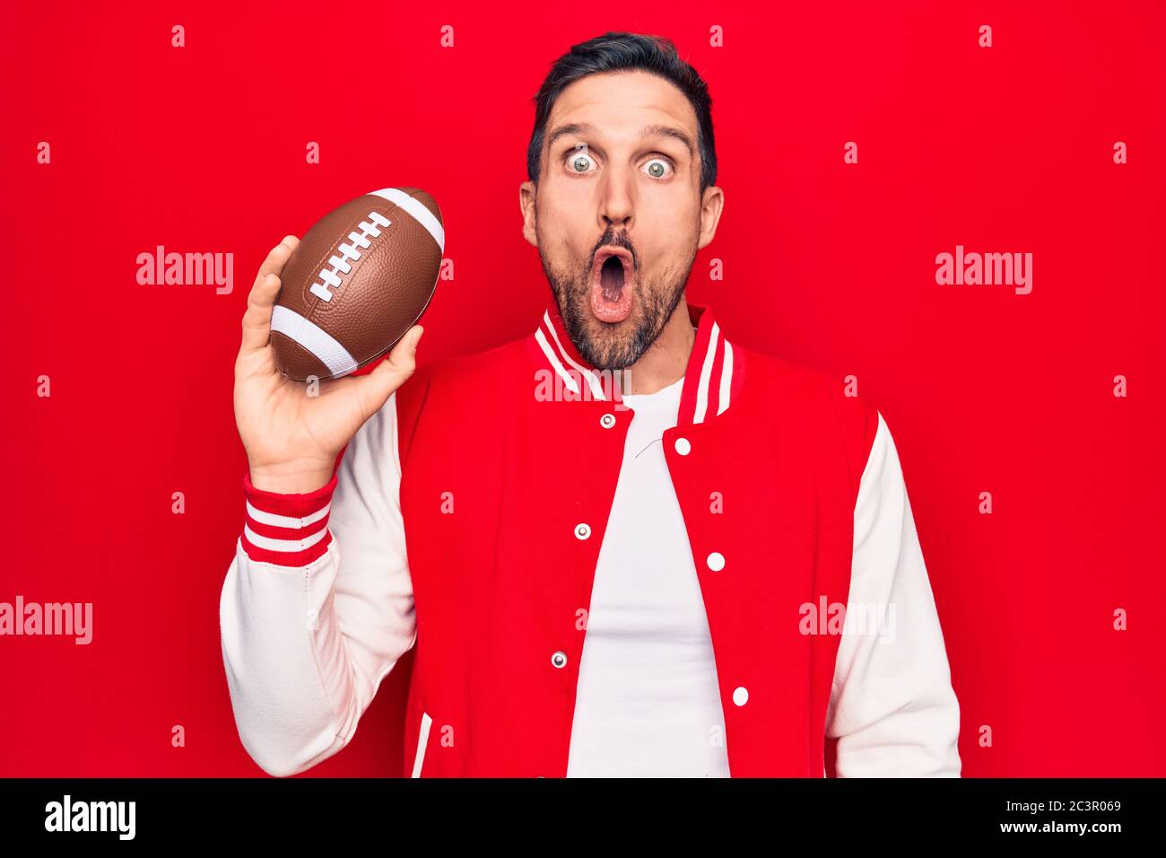 Young handsome player man playing rugby using football ball over ...