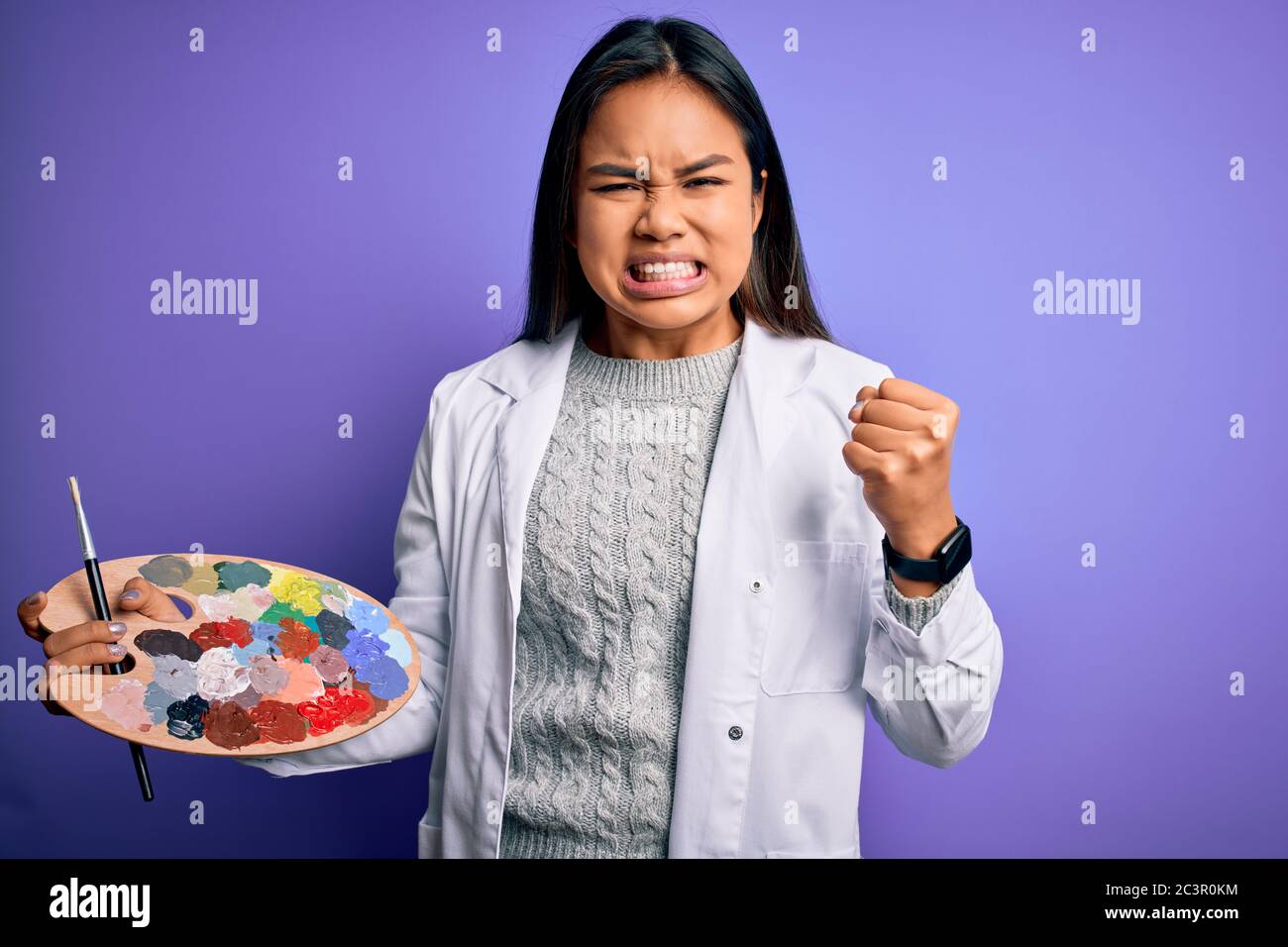 Young asian artist girl painting using paintbrush and palette with ...