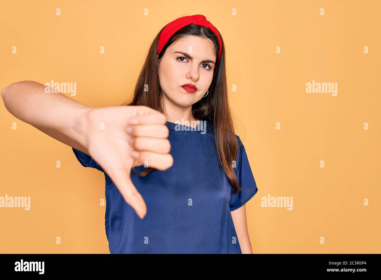 Young beautiful brunette woman wearing red lips over yellow background ...