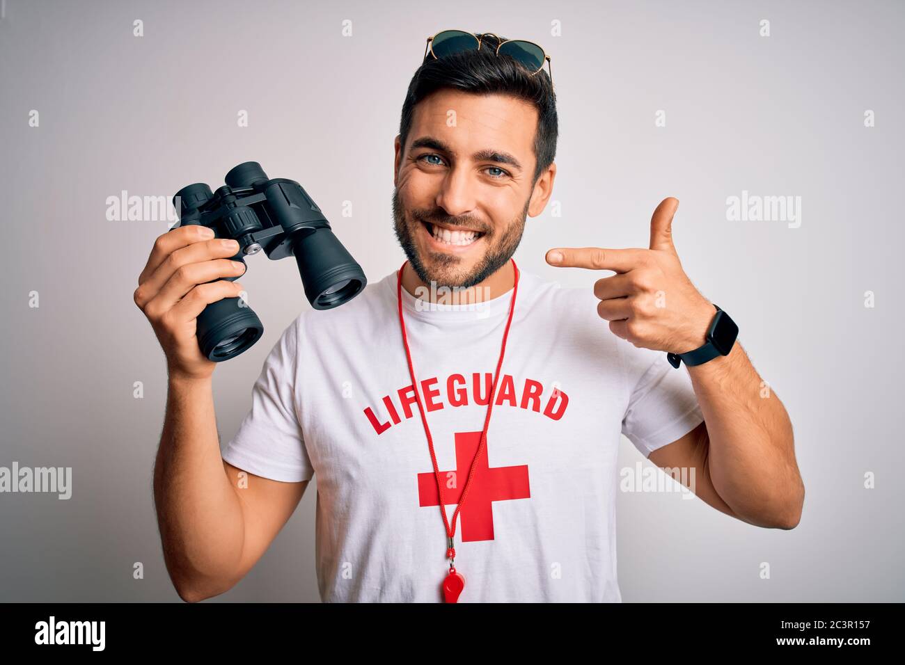 Young lifeguard man with beard wearing t-shirt with red cross and ...