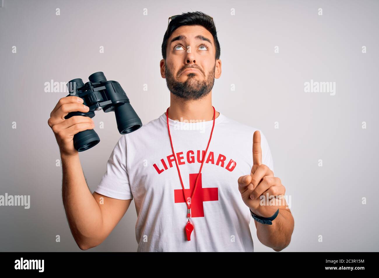 Young lifeguard man with beard wearing t-shirt with red cross and ...
