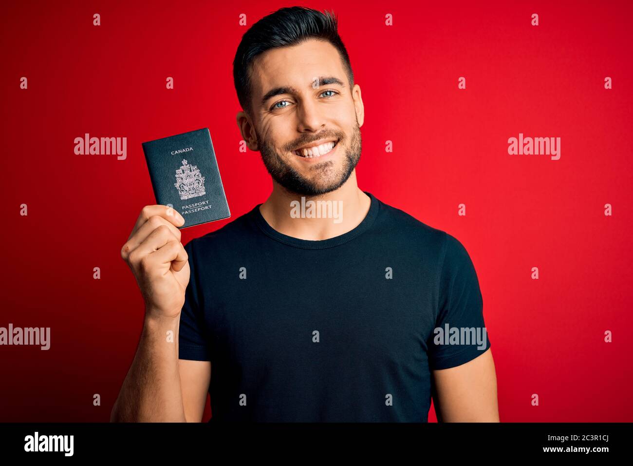 Young handsome tourist man holding canada canadian passport id over red ...