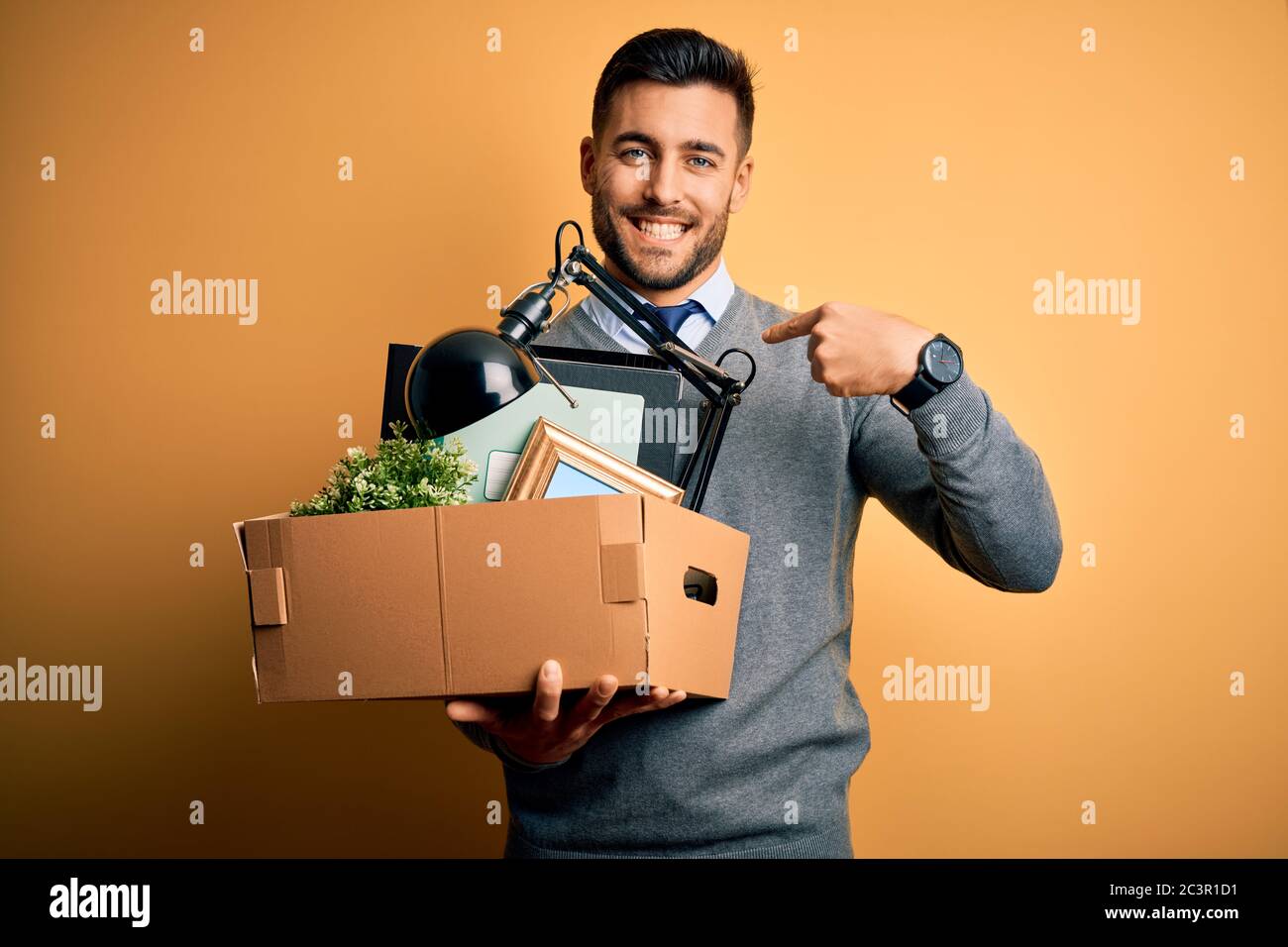 Young business man holding office box being fired from job over yellow ...