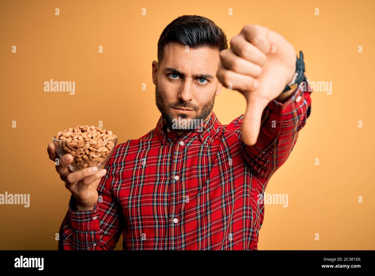Young handsome man holding bowl with healthy peanuts over isolated ...