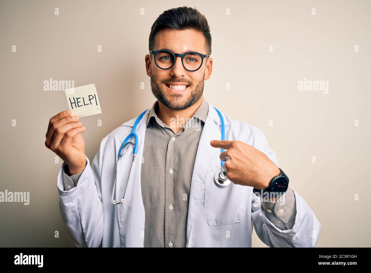 Young doctor man wearing stethoscope holding help note over isolated ...