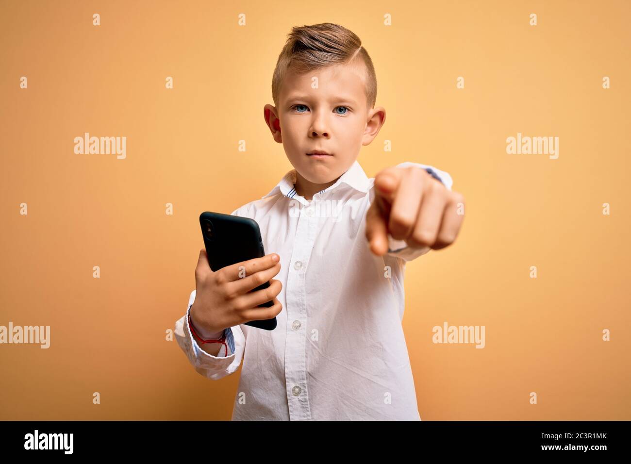 Young little caucasian kid using smartphone and looking at the screen ...