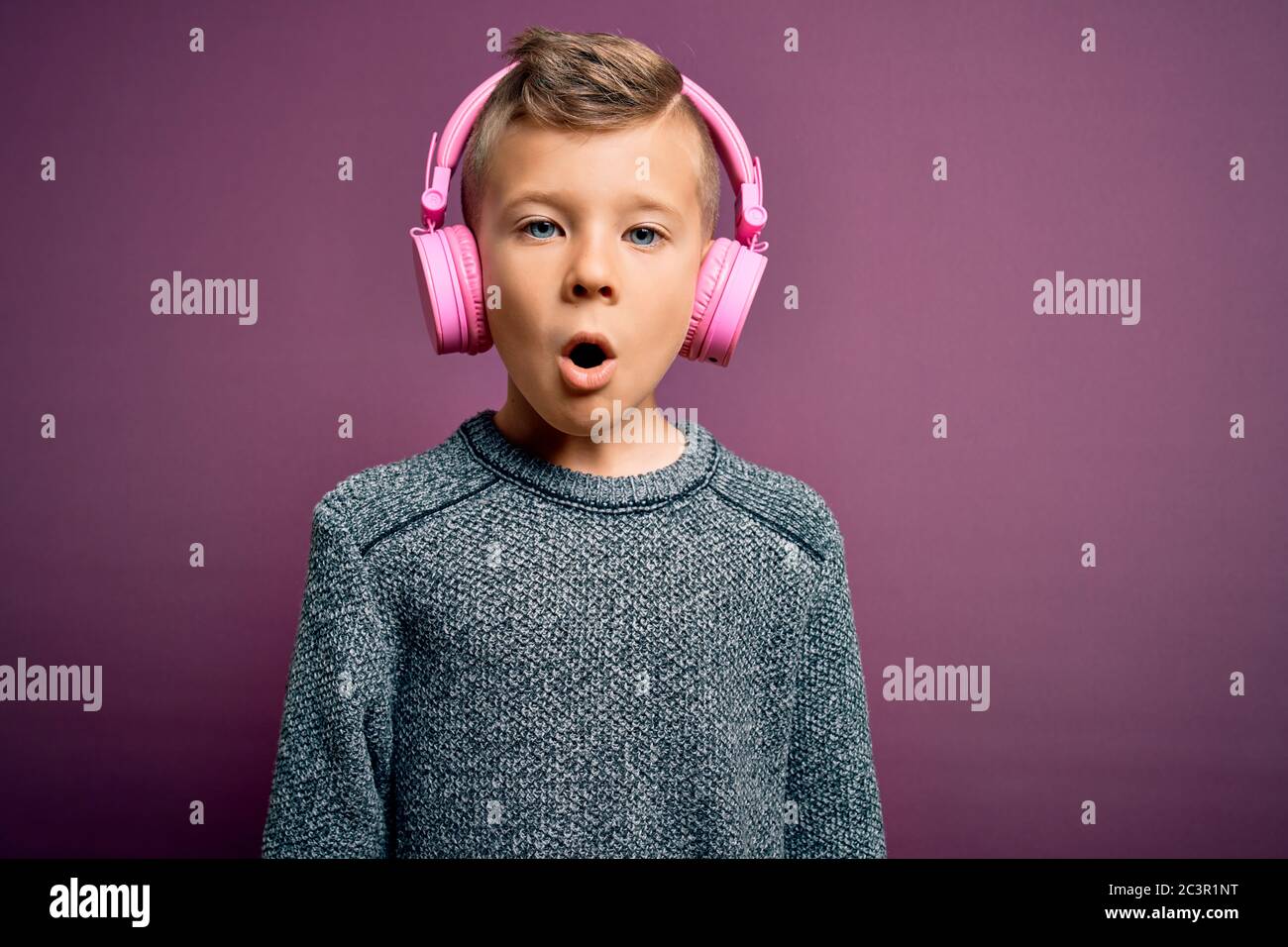 Young little caucasian kid wearing headphones listening to music over ...