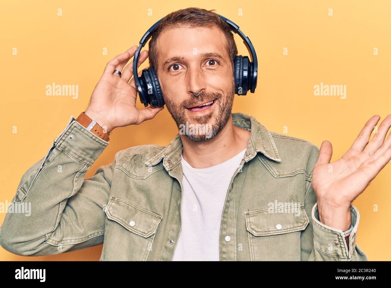 Young handsome man listening to music using headphones celebrating ...