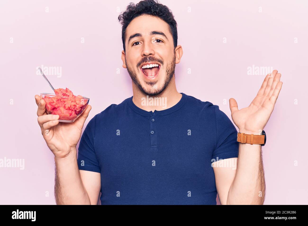 Young hispanic man holding ice cream celebrating victory with happy ...