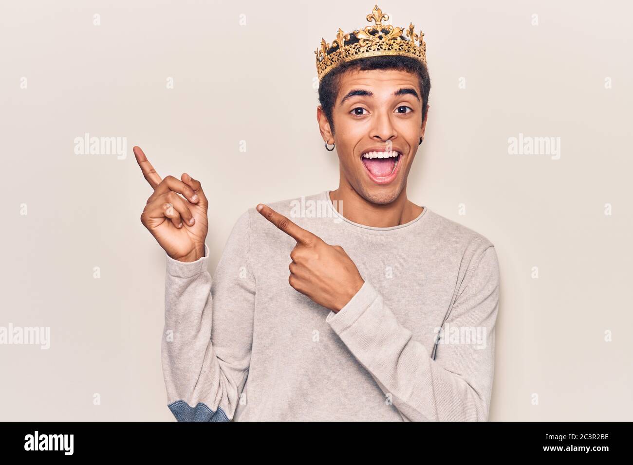 Young african amercian man wearing prince crown smiling and looking at ...