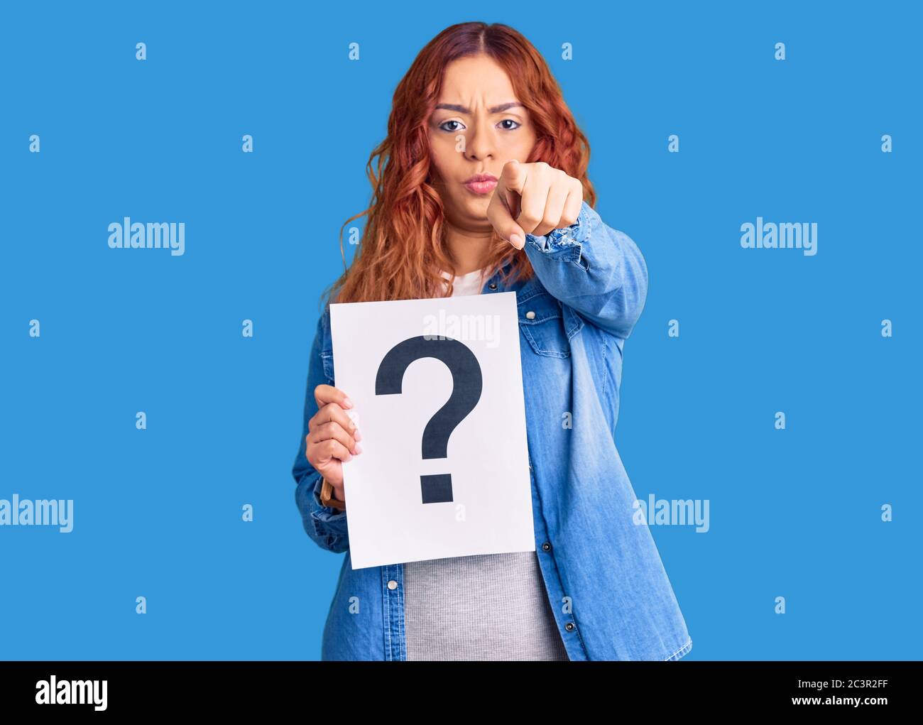 Young latin woman holding question mark pointing with finger to the ...