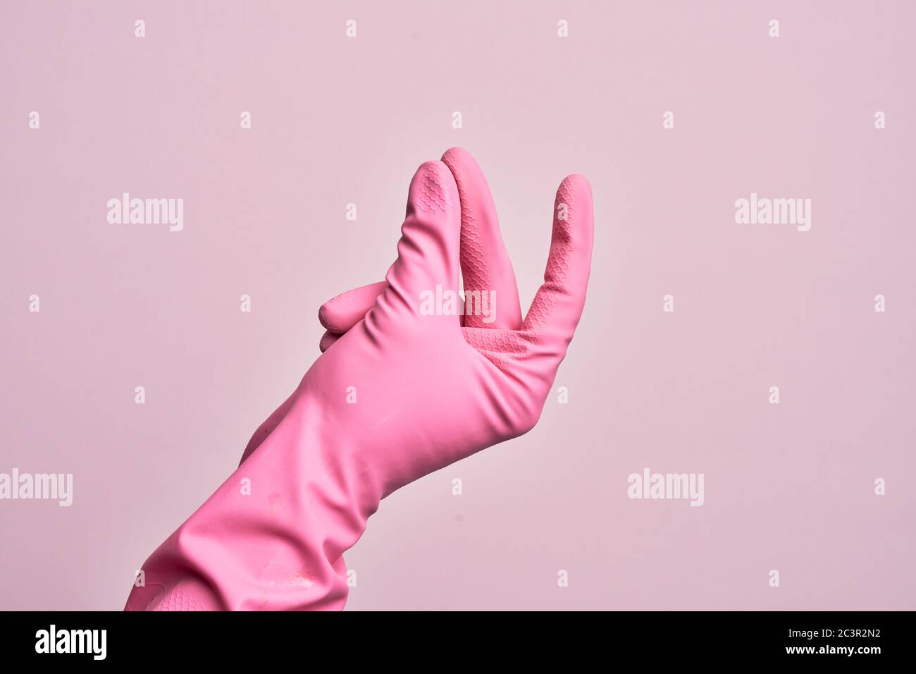 Hand of caucasian young man with cleaning glove over isolated pink ...