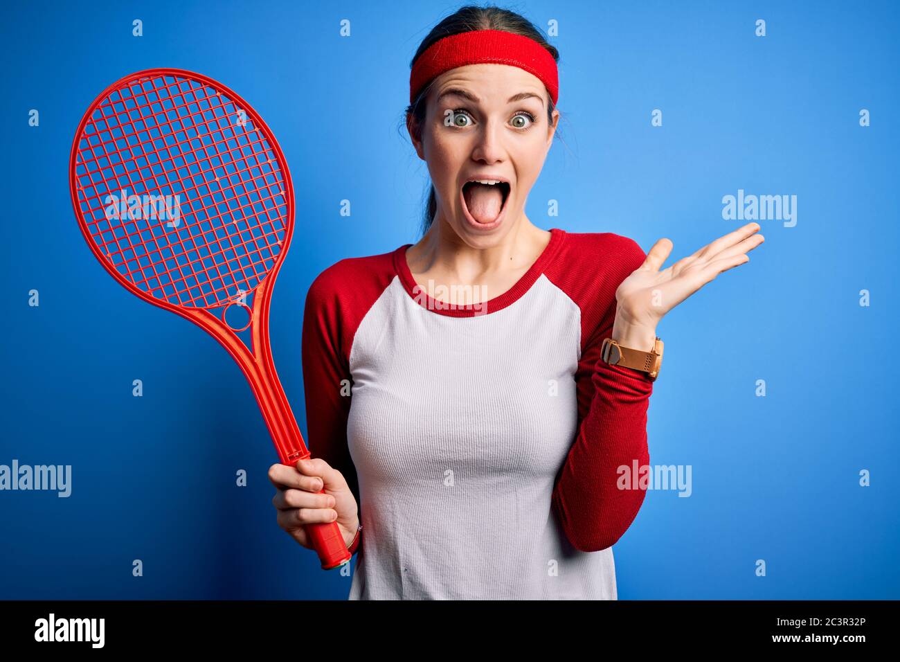 Young beautiful redhead sportswoman playing tennis using racket over ...