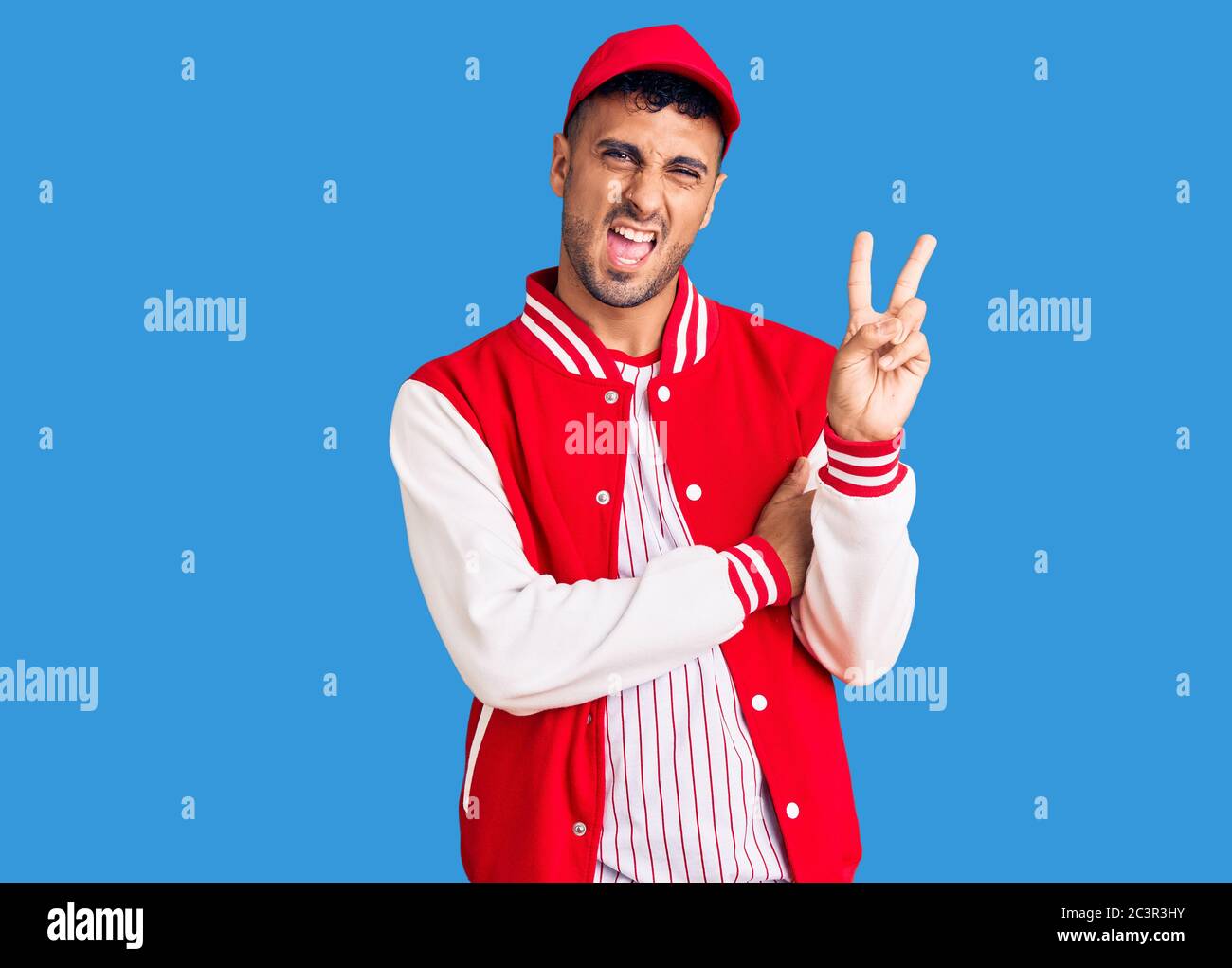 Young hispanic man wearing baseball uniform smiling with happy face ...