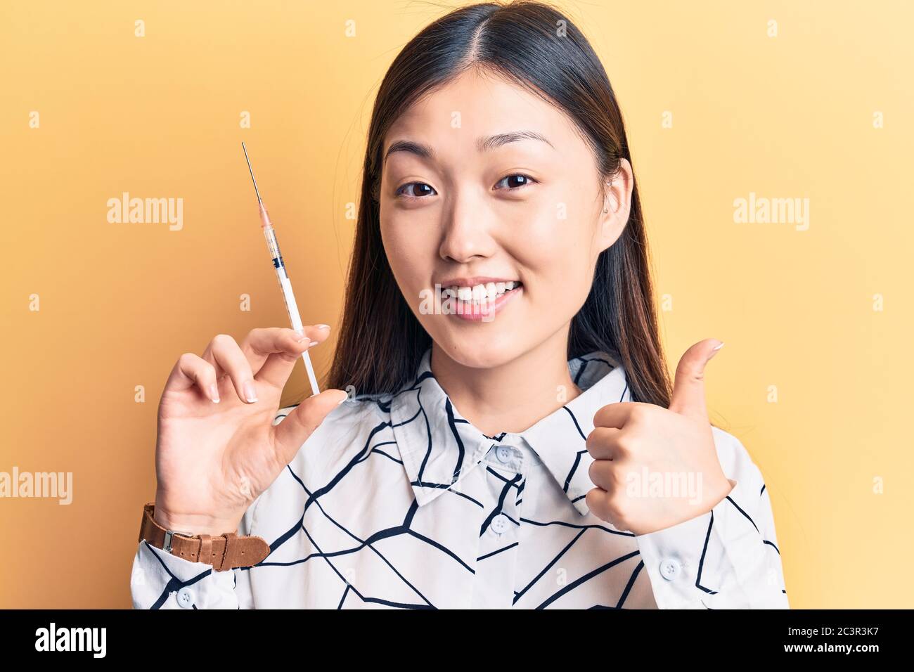 Young beautiful chinese woman holding syringe smiling happy and ...