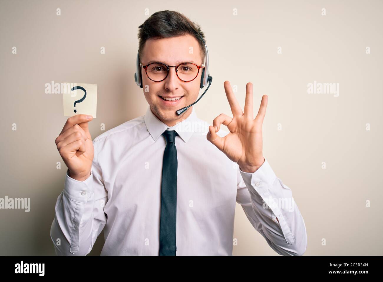 Young call center operator man wearing headset holding paper note with ...