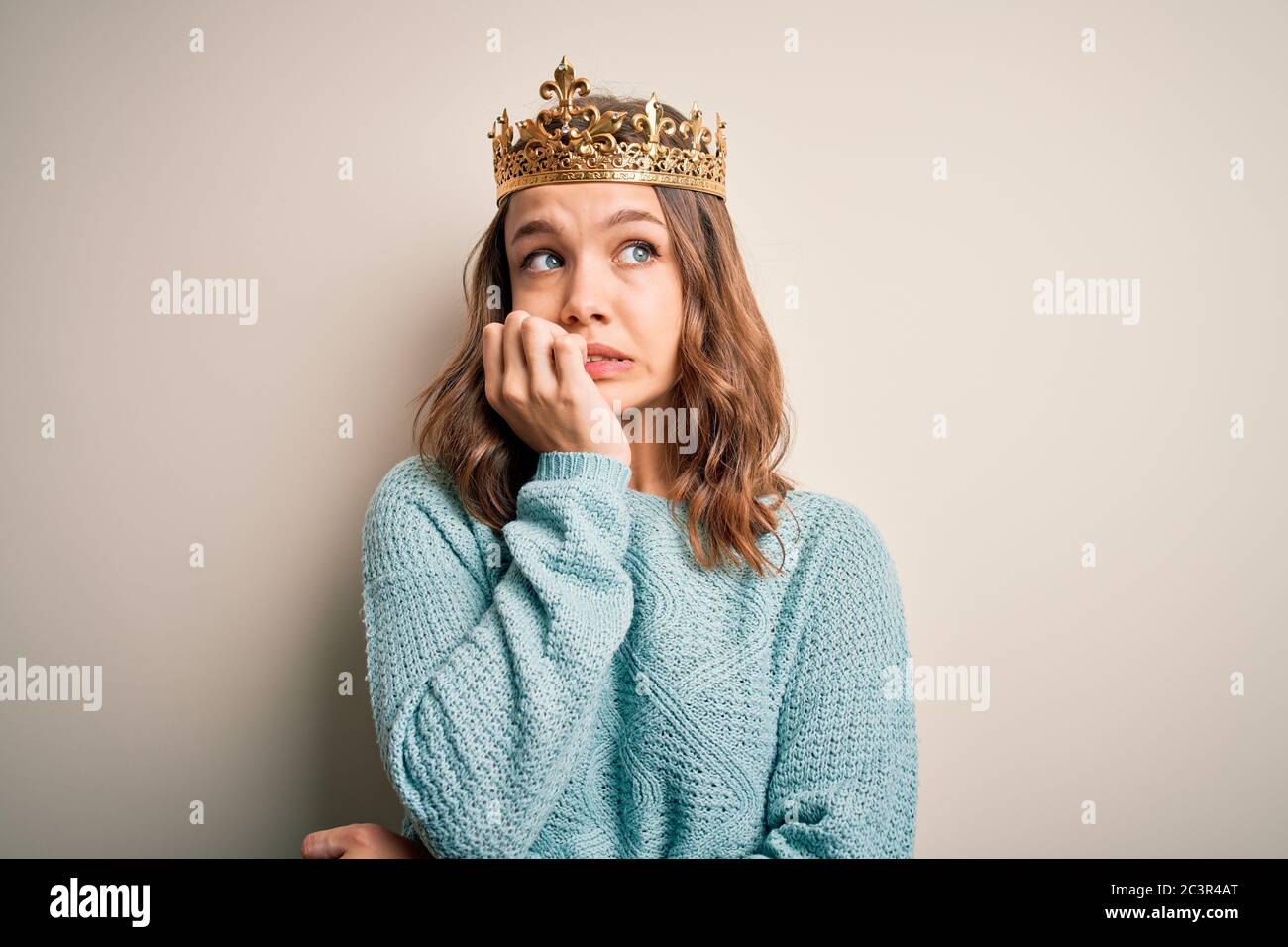 Young blonde girl wearing queen golden crown over isolated background ...