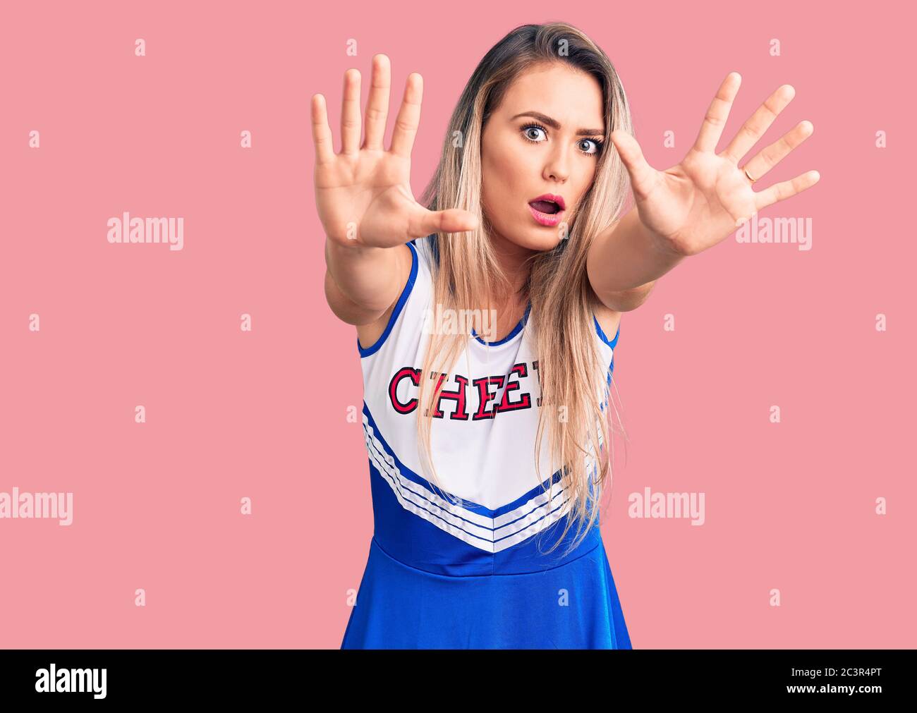 Young beautiful blonde woman wearing cheerleader uniform doing stop ...