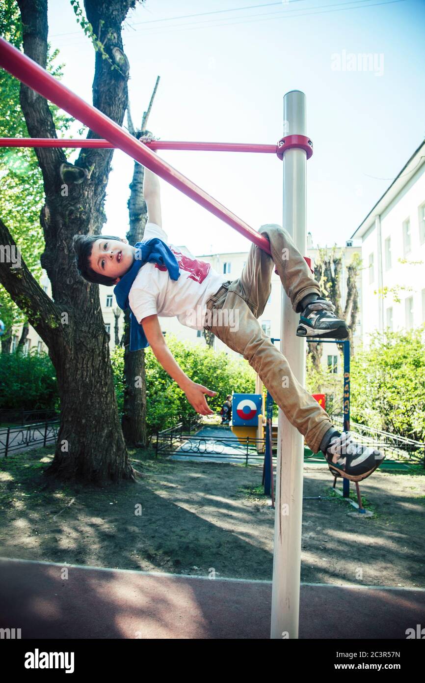 little cute blond boy hanging on playground outside, alone training ...
